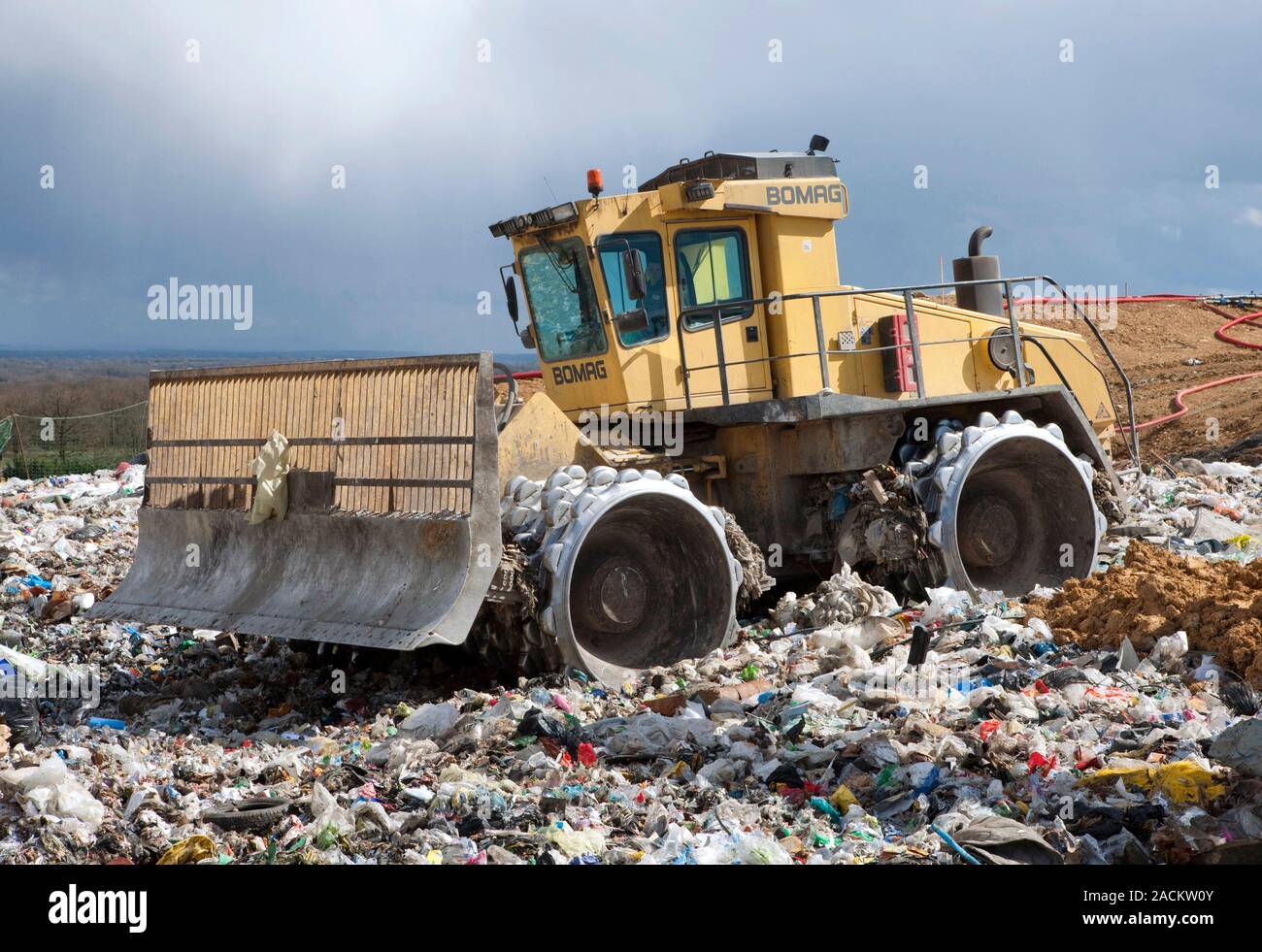 Landfill site. Vehicle compacting waste at a landfill site in ...