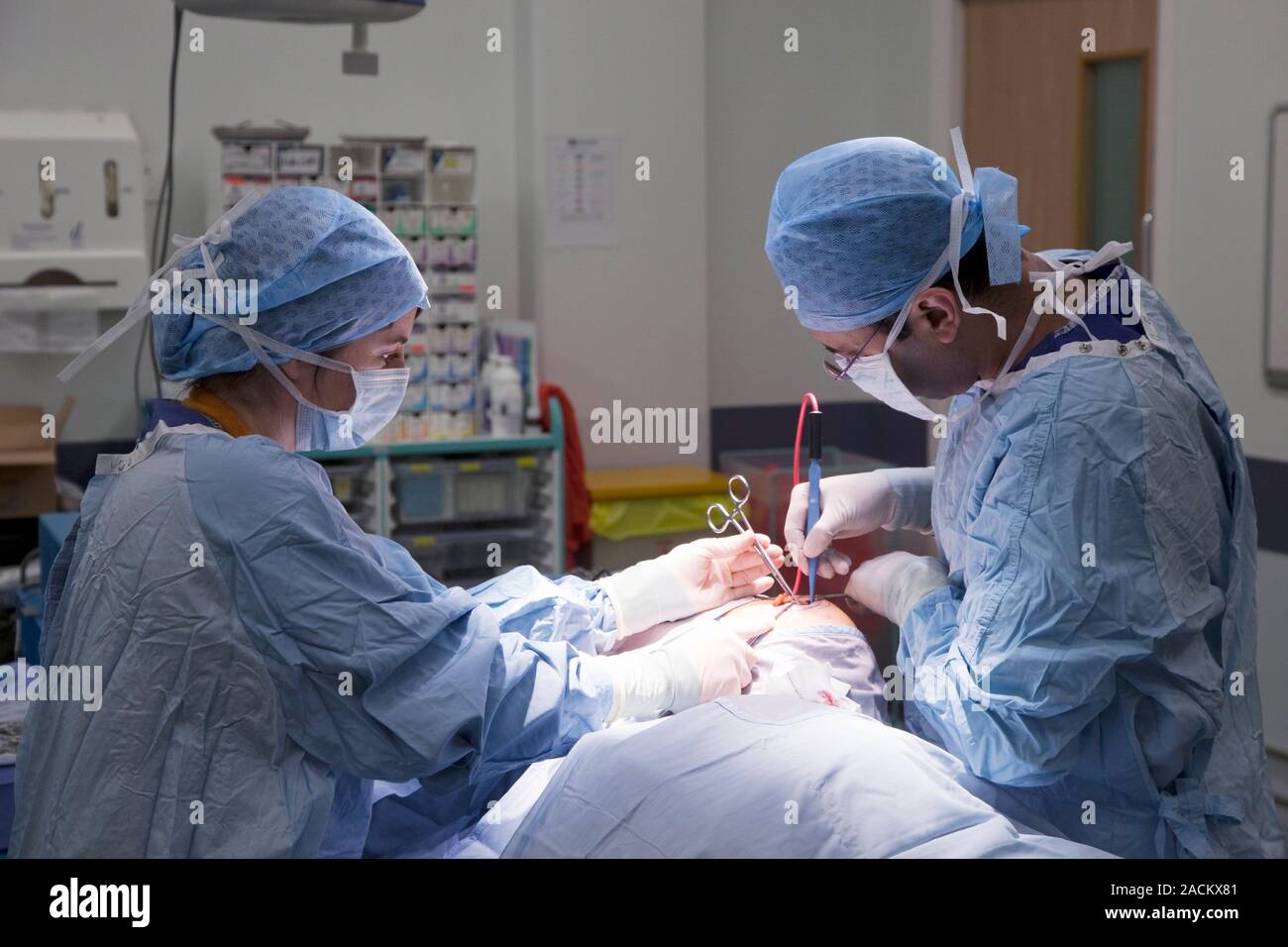 Surgeon performing surgery to remove (excise) a lesion in the shoulder ...