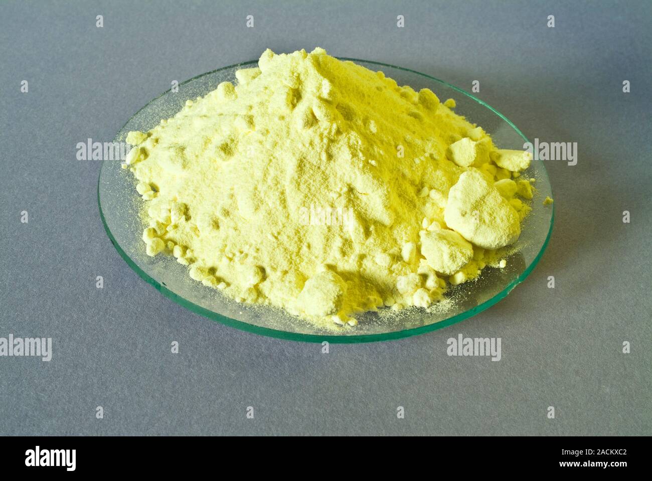 Sulphur powder on a watch glass. Sulphur is a reactive chemical element ...