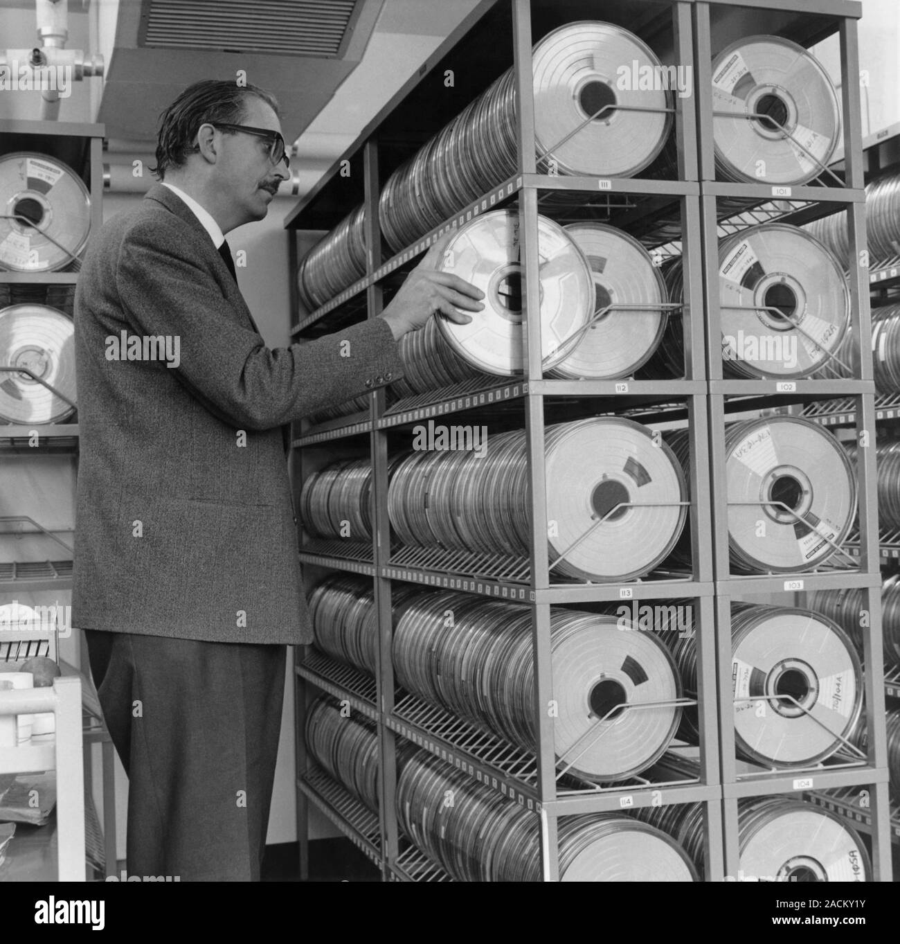 Magnetic computer tape storage racks. Met Office employee selecting a ...