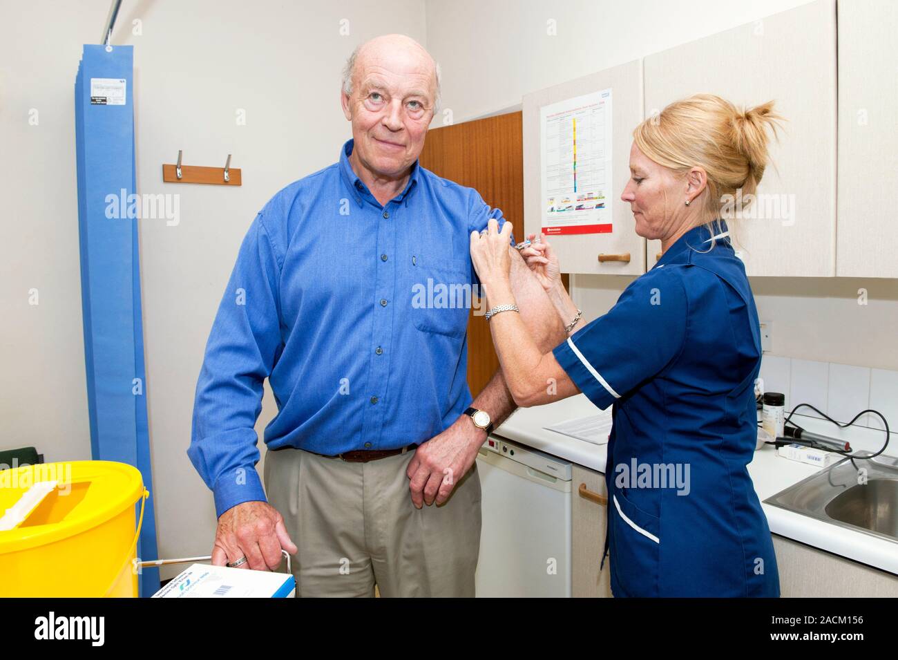 Seasonal influenza (flu) vaccination. Nurse injecting the upper arm of ...