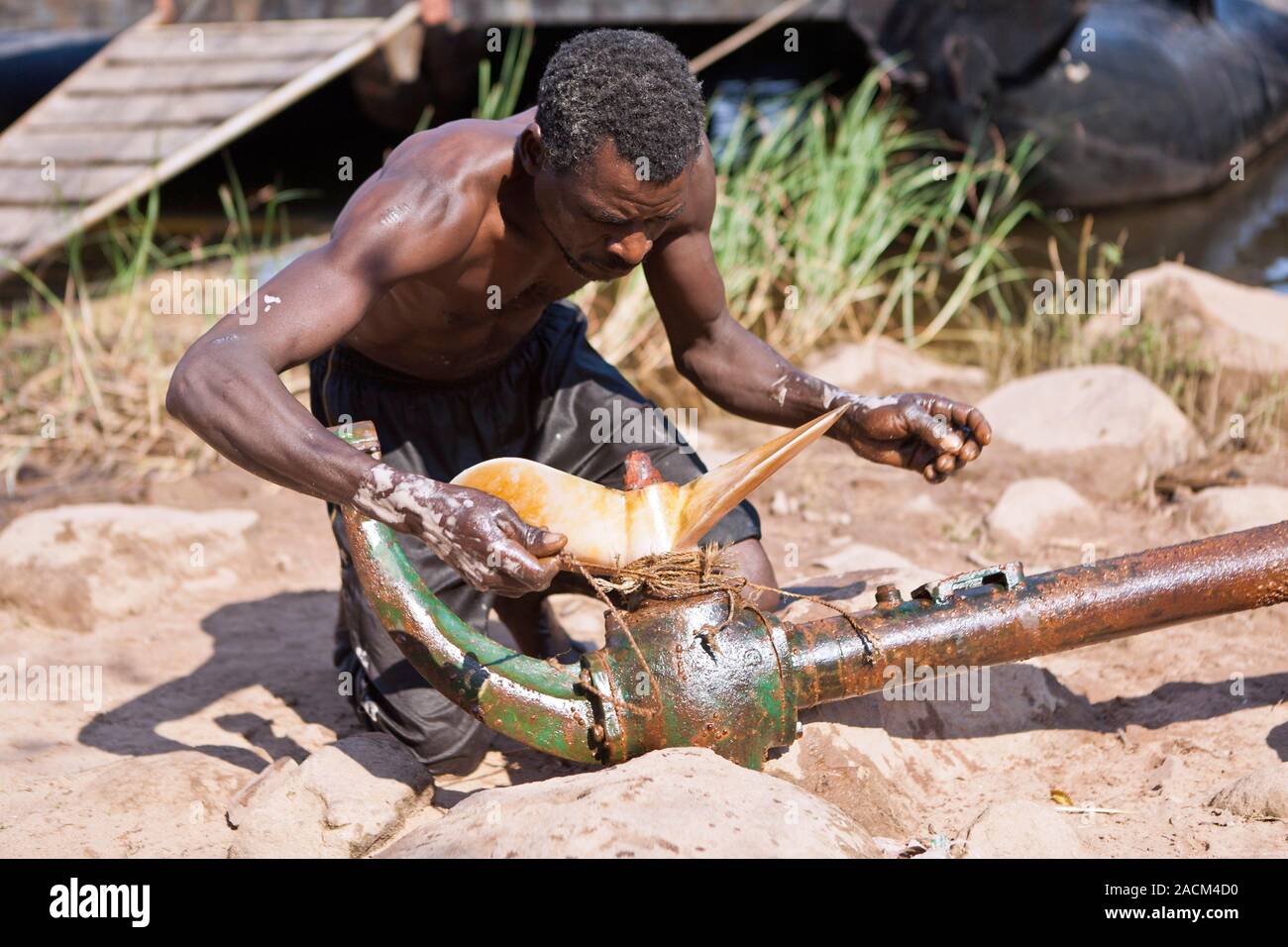 Fisherman untangling a net form the propeller of his fishing boat ...