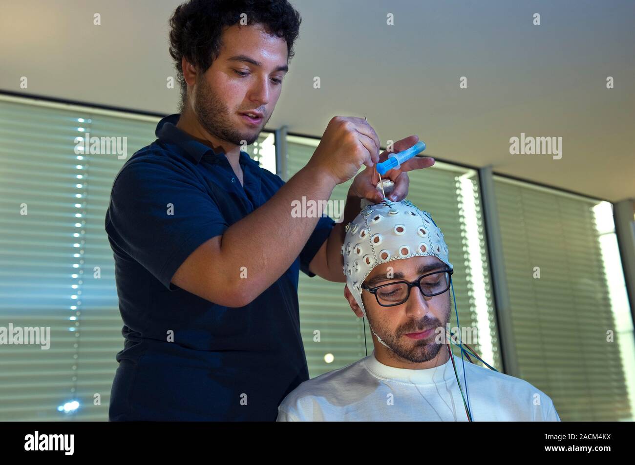 Thought-controlled wheelchair. Researcher attaching EEG electrodes to a ...