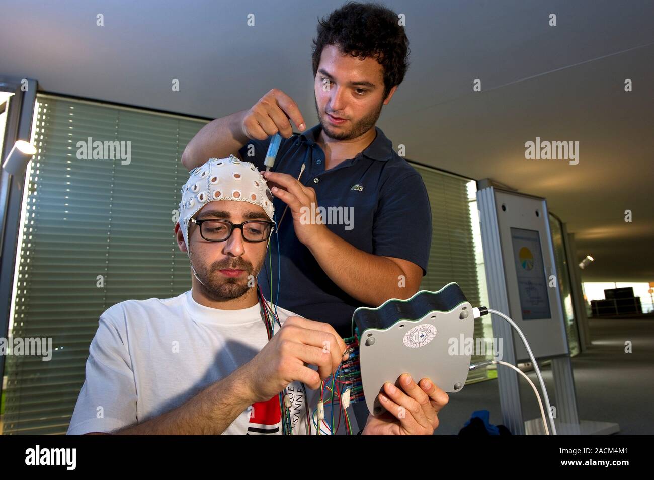 Thought-controlled wheelchair. Researcher attaching EEG electrodes to a ...
