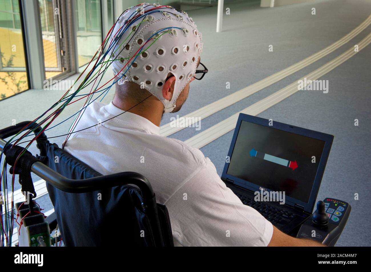 Thought-controlled wheelchair. Researcher testing a brain-machine ...