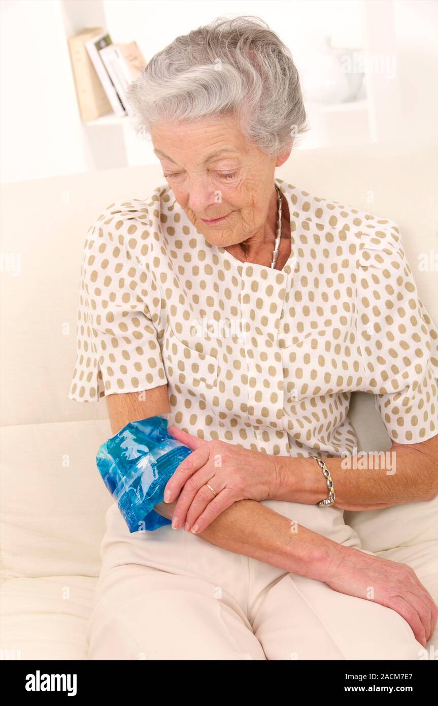 Sprained elbow. 81-year-old woman holding a cold compress to her ...