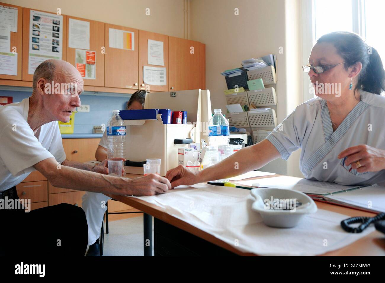 Tuberculosis clinic. Male patient receiving his morning medication in a ...