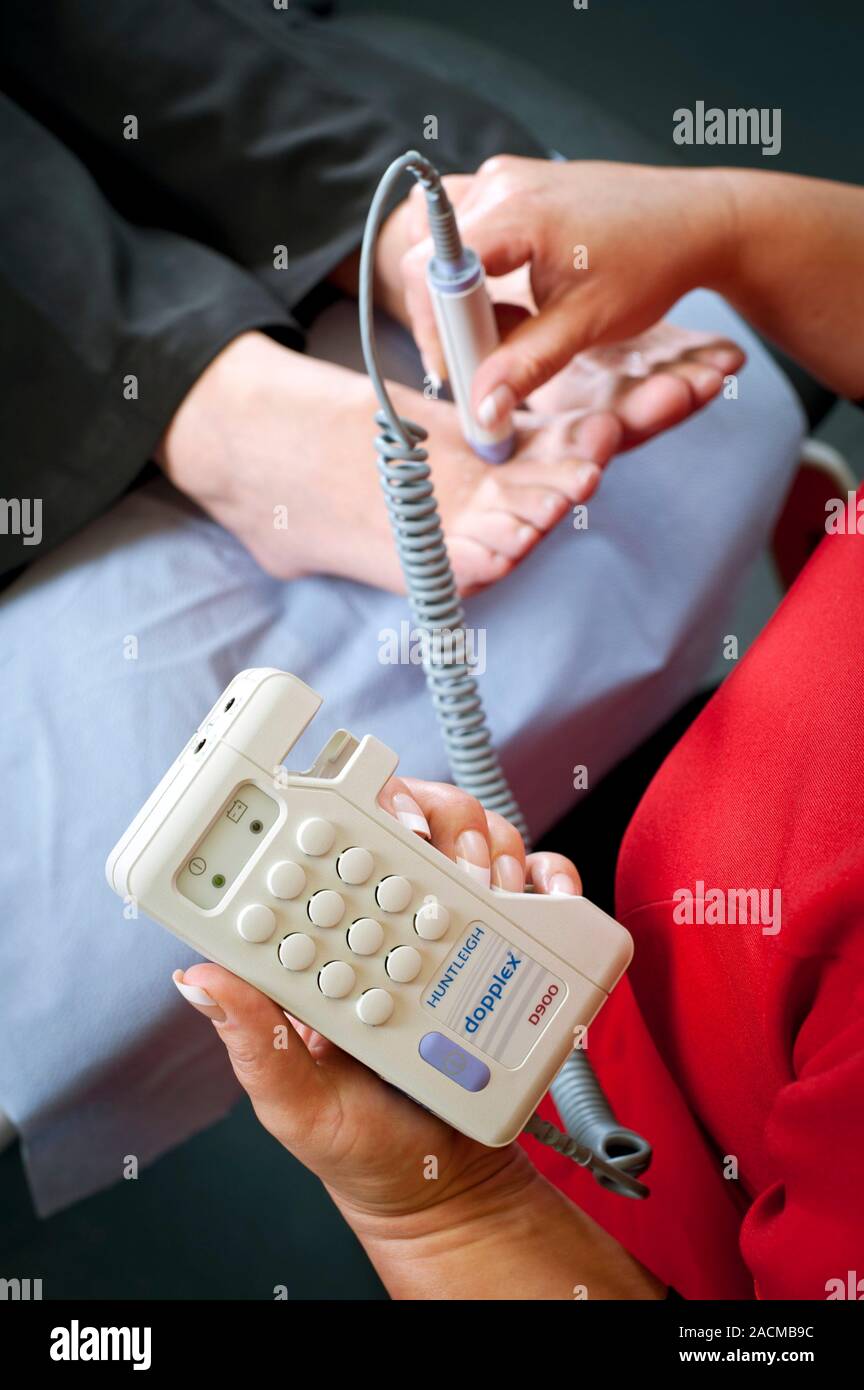 Foot pulse test in diabetic patient. Nurse using a portable Doppler ...
