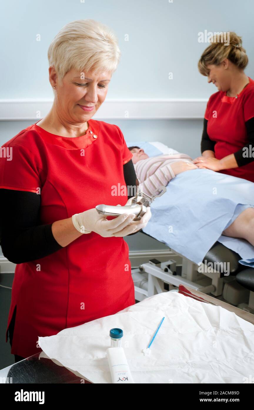 Smear test. Practice nurses performing a smear test on a patient. A ...