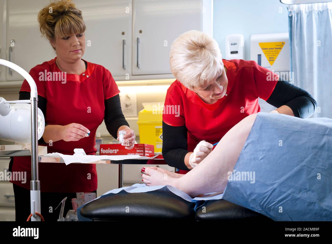 Smear test. Practice nurses performing a smear test on a patient. A ...