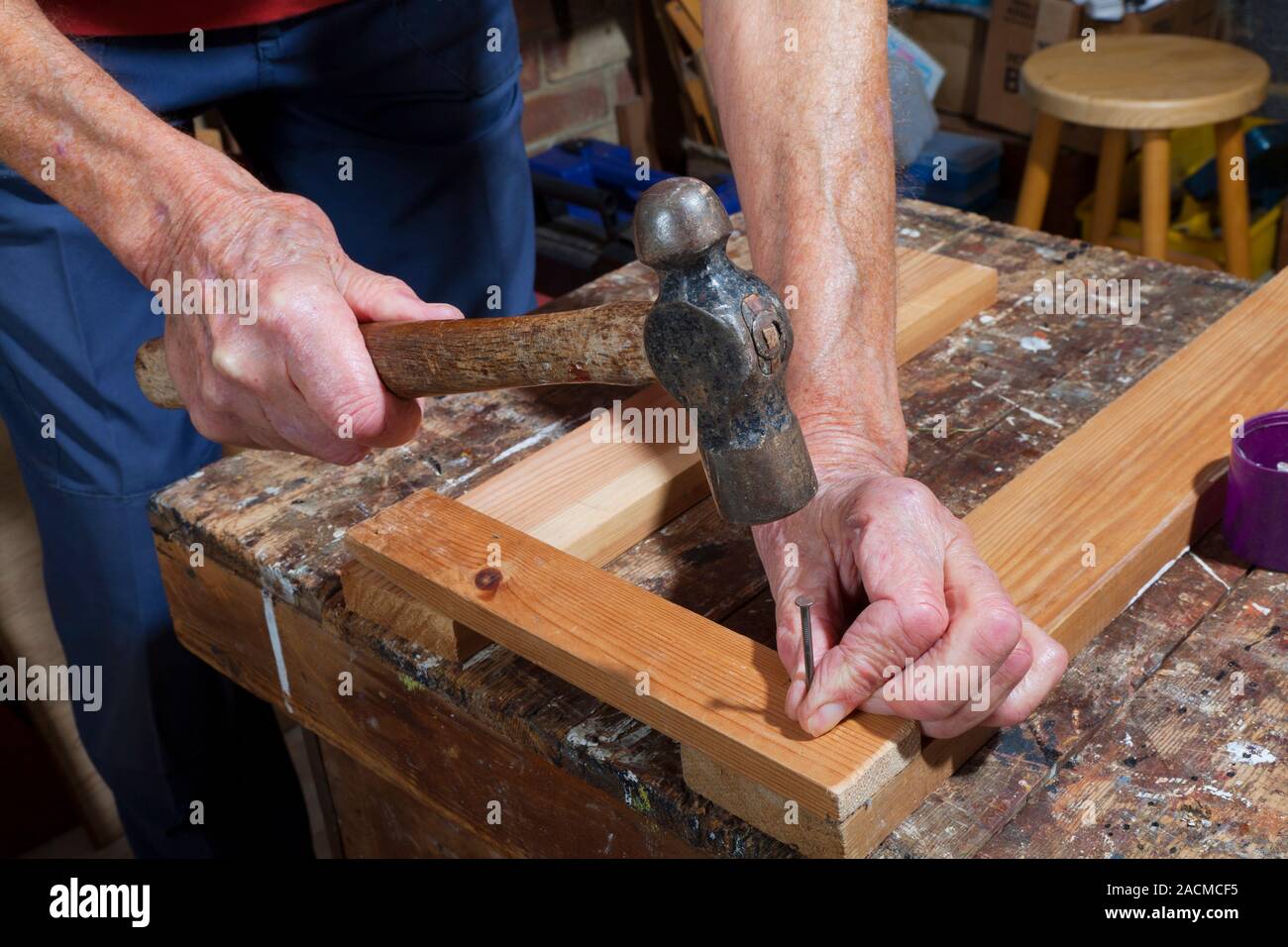 Elderly man using a hammer. Hands of an elderly man in his workshop ...