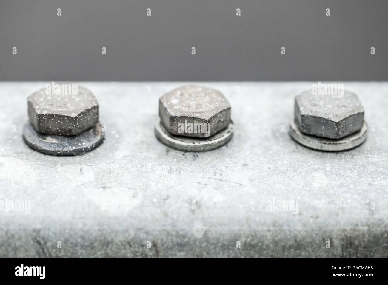Abstract industrial background with three gray bolts in a row, close-up ...