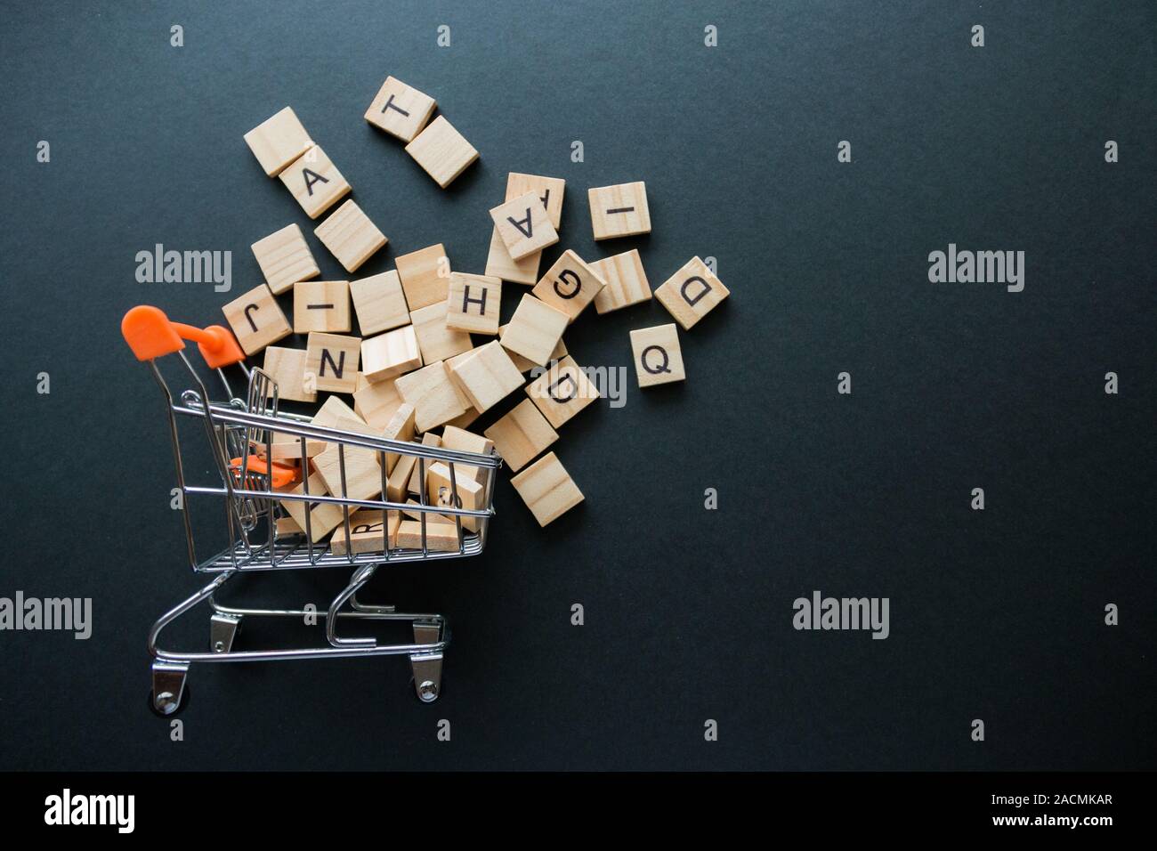 A pile of wooden letters in a small cart on the surface of a dark ...