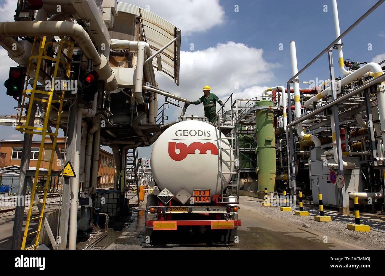 Chemical industry worker on top of a road tanker that is being filled ...
