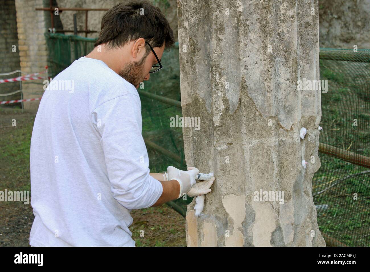 Roman column preservation. Archaeologist using a syringe to inject ...