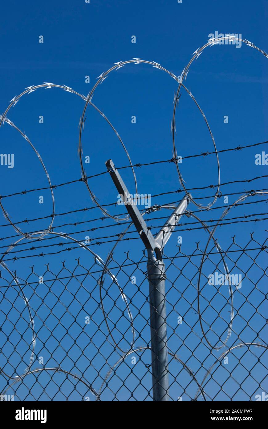 Security fence, topped with razor wire, surrounding industrial premises ...