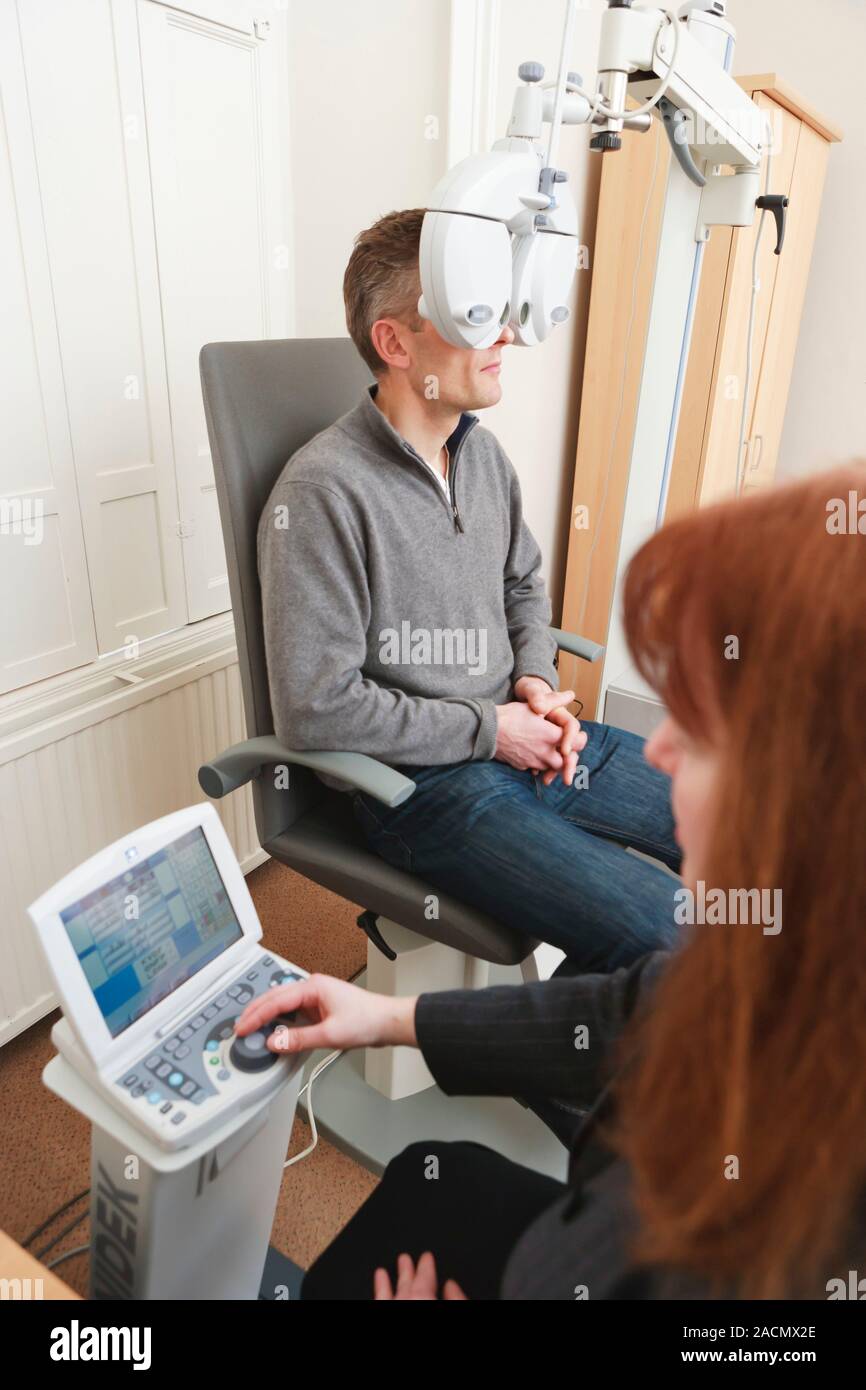 Patient having an eye test with refraction eye test equipment Stock ...