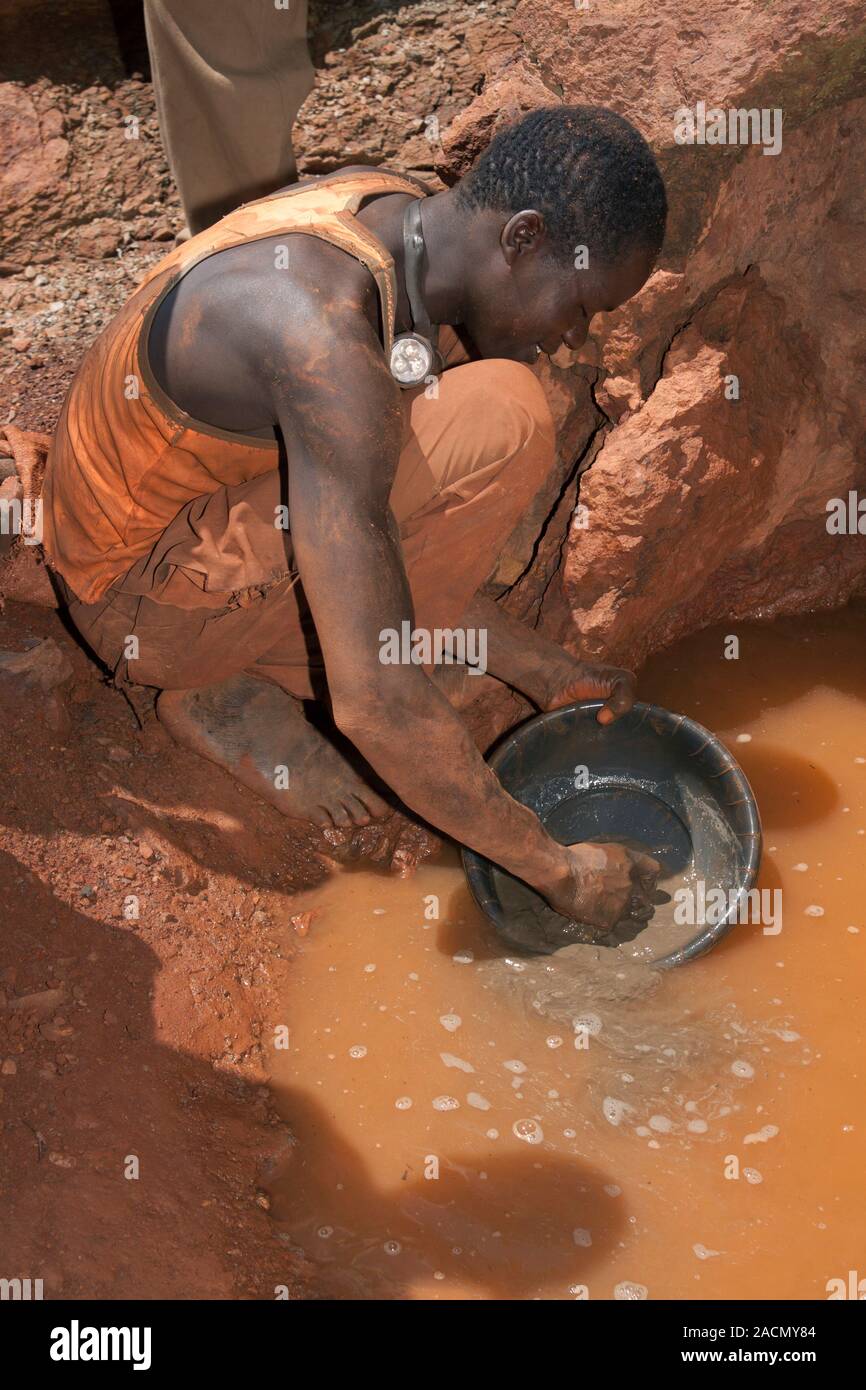 Artisan miner panning for gold. He is working on the site of a mine ...