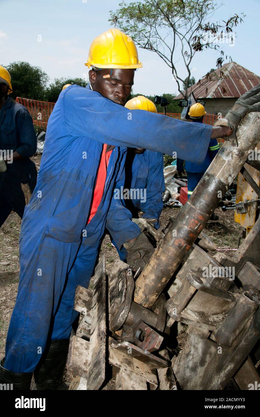 Mineral exploration drilling. Workers removing the drill rods from a ...