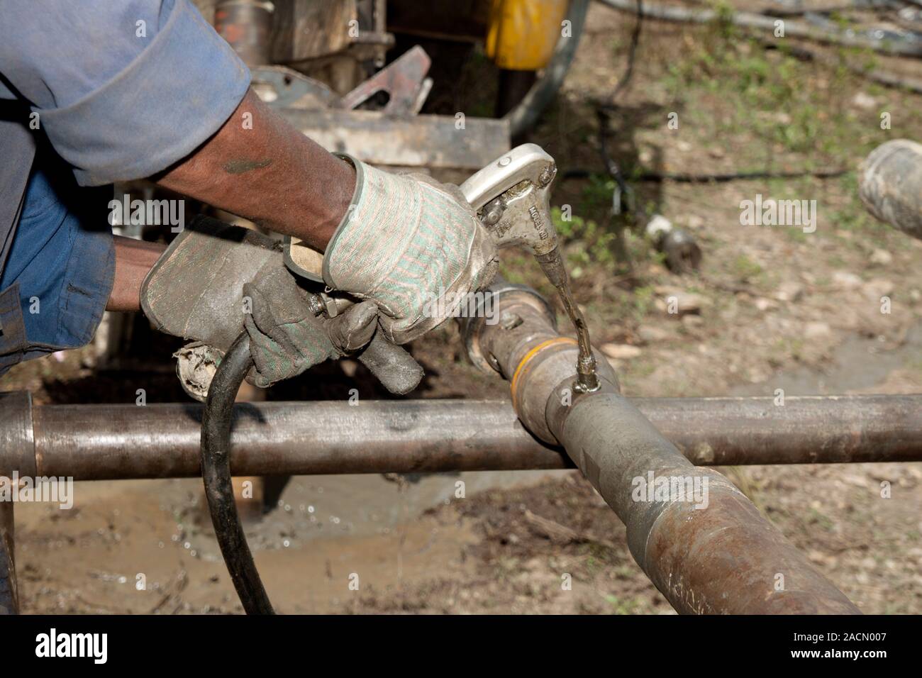 Mineral exploration drilling. Workers removing the drill rods from a ...