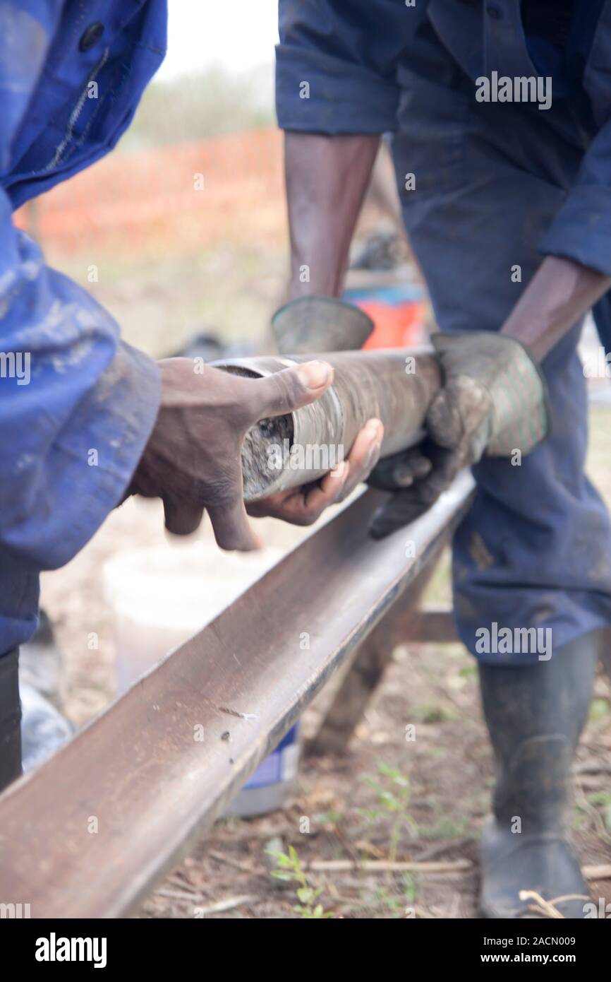 Mineral exploration drilling. Workers removing the drill rods from a ...