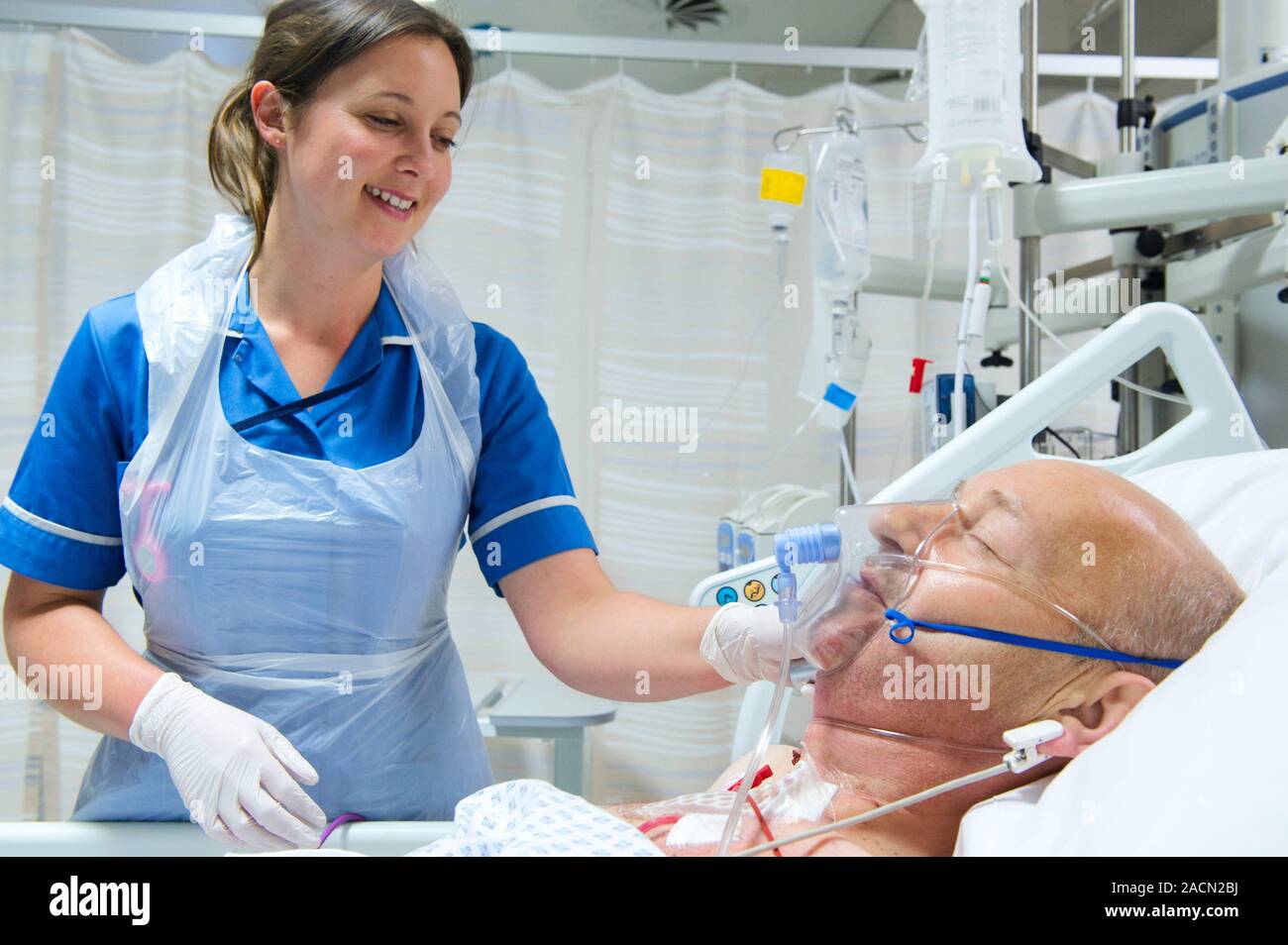 Intensive care patient. Nurse attending to a male patient in the ...