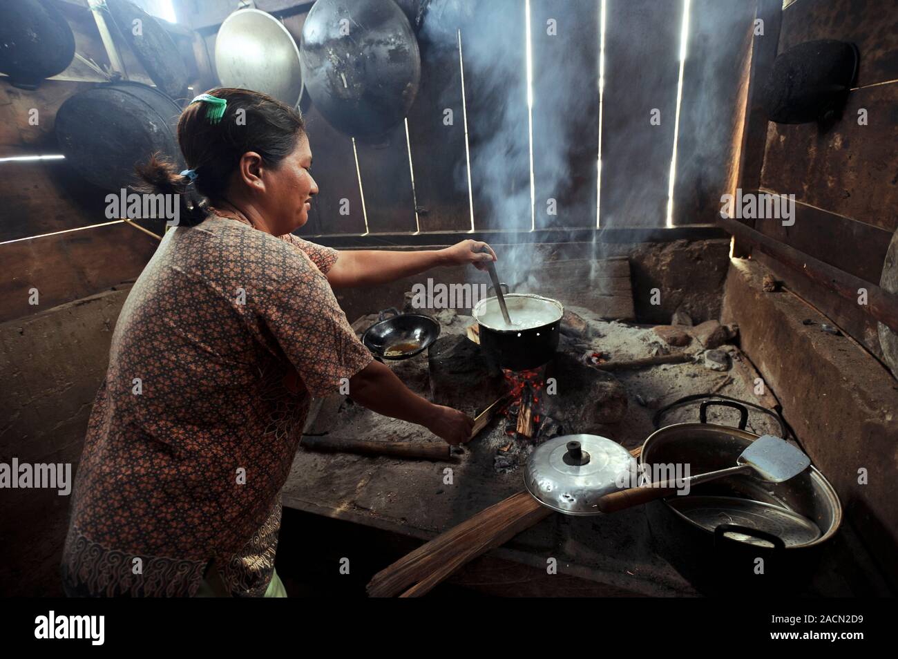Home cooking. Woman cooking on a wood fire at her home in Bangga ...