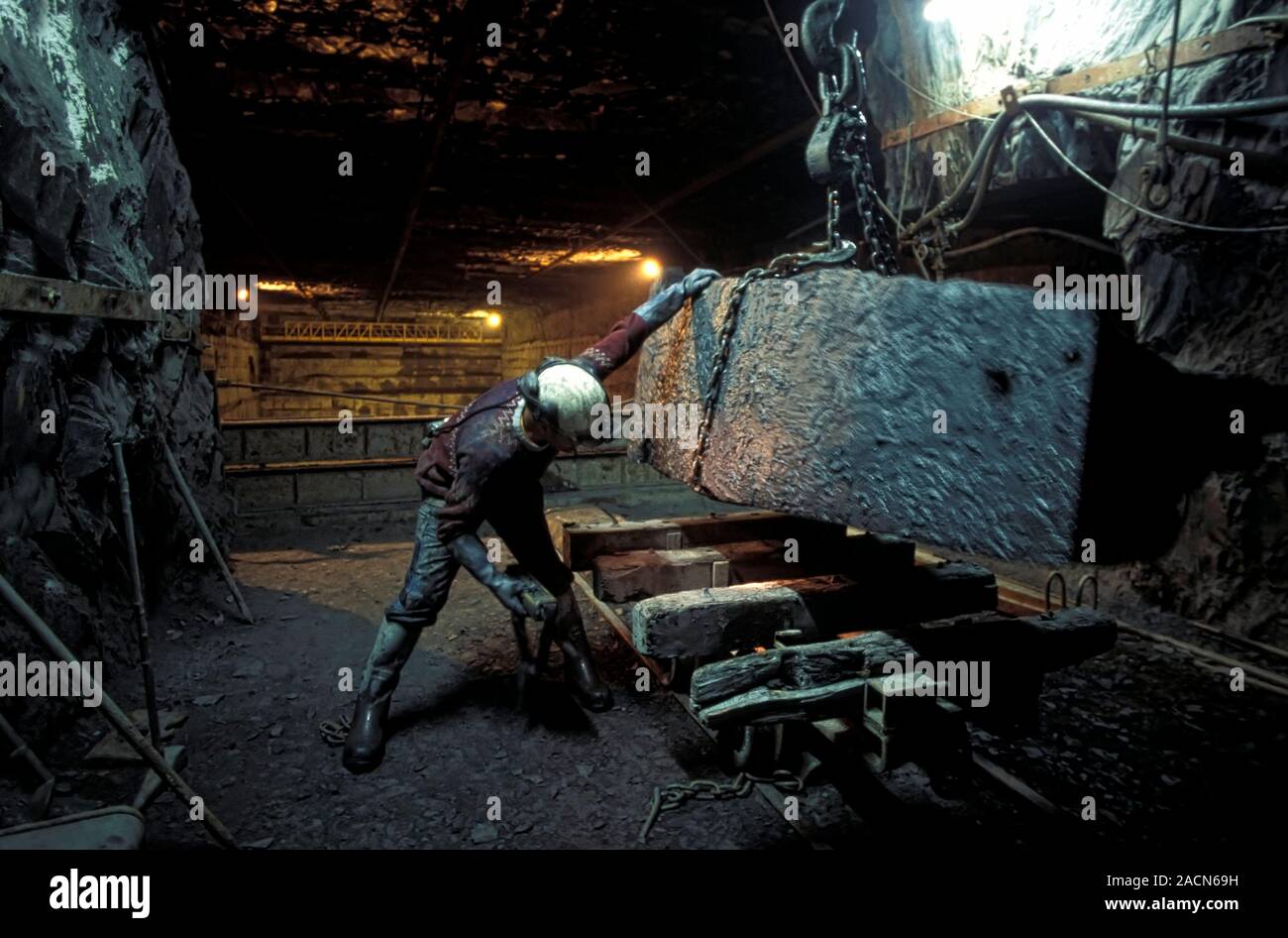 Slate mining. Worker positioning a large slab of slate on a track to ...