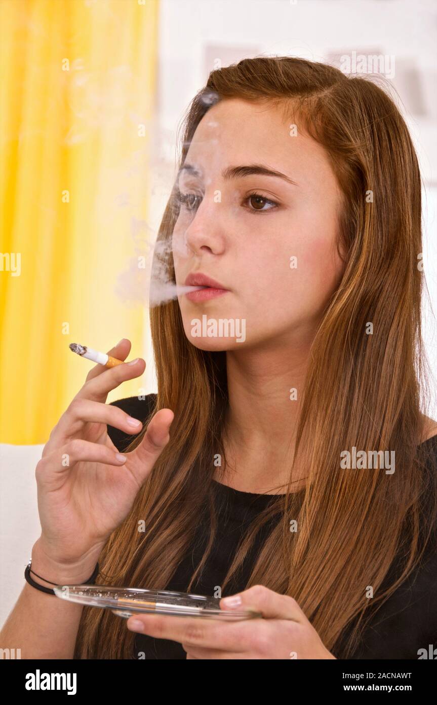 Teenager smoking. Teenage girl smoking a tobacco cigarette. Tobacco contains cancer-causing ...