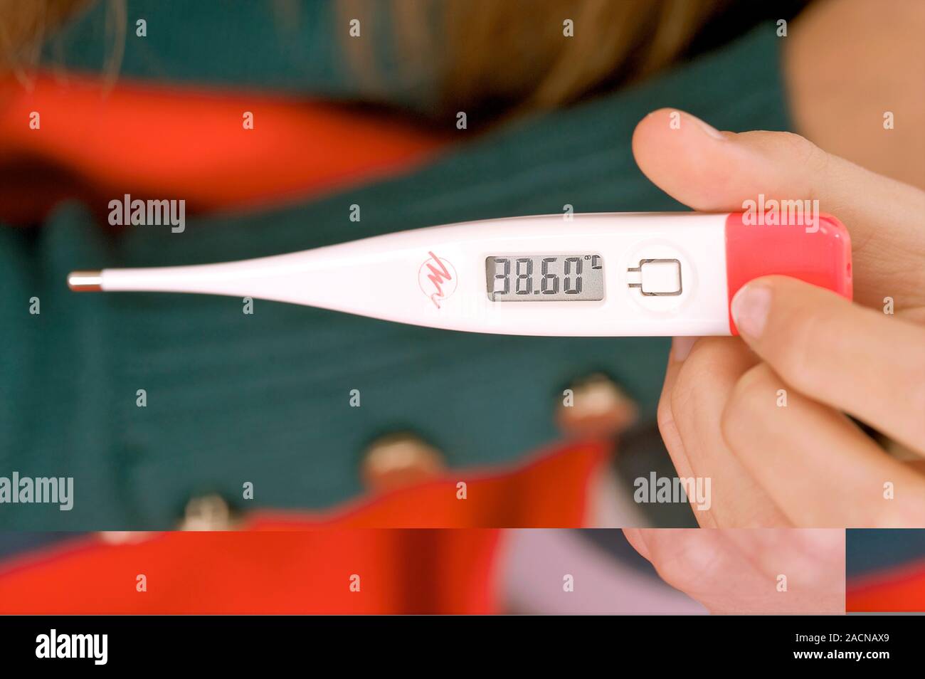 Digital thermometer showing fever, held in a teenage girl's hand. The ...