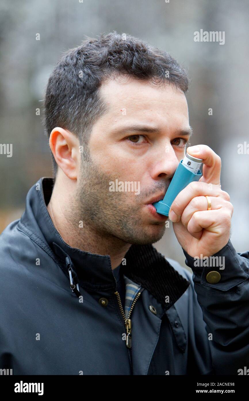 Asthma inhaler use. Man using an inhaler to treat an asthma attack ...