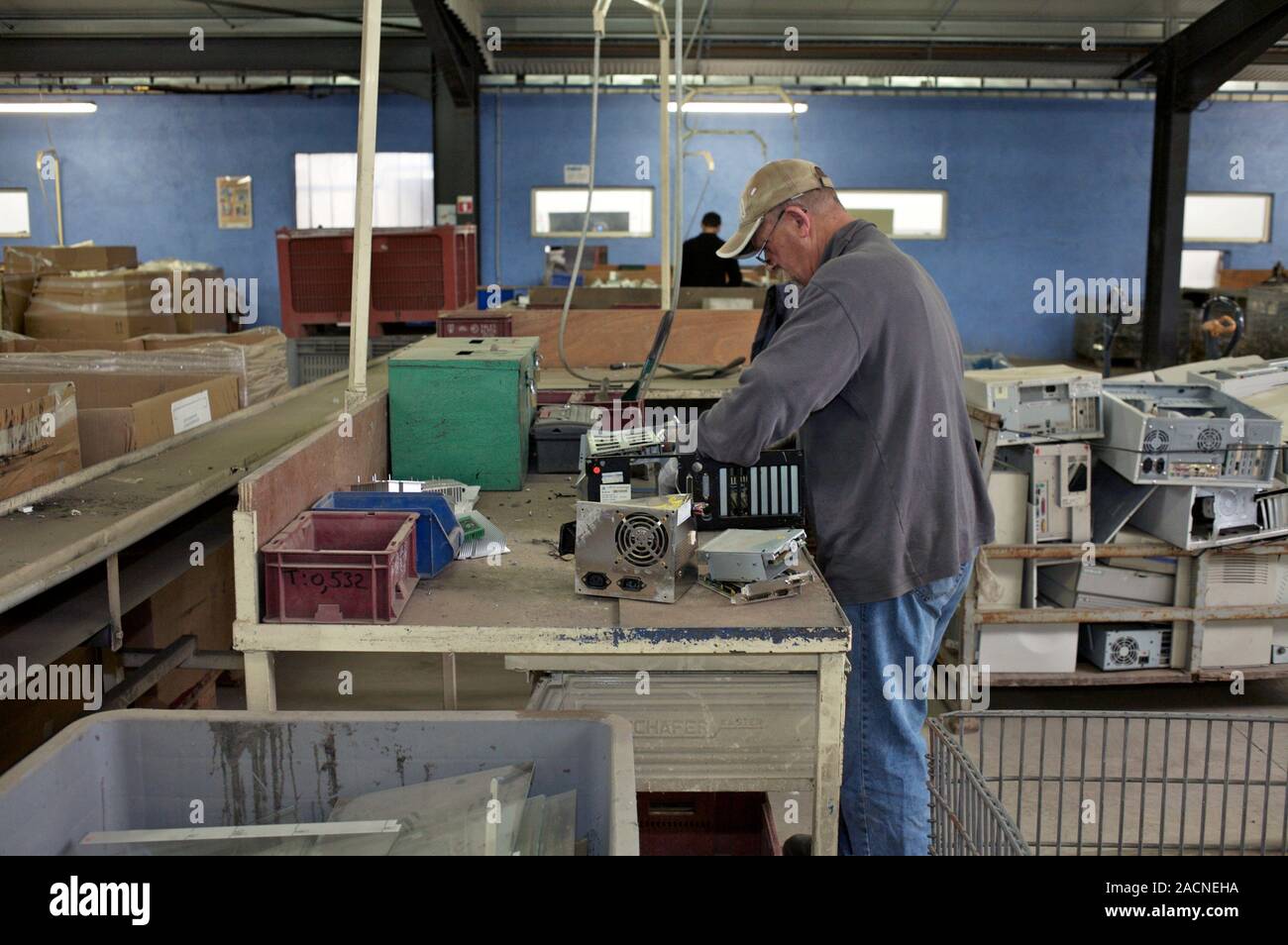 Computer equipment recycling centre. Worker dismantling old computer ...