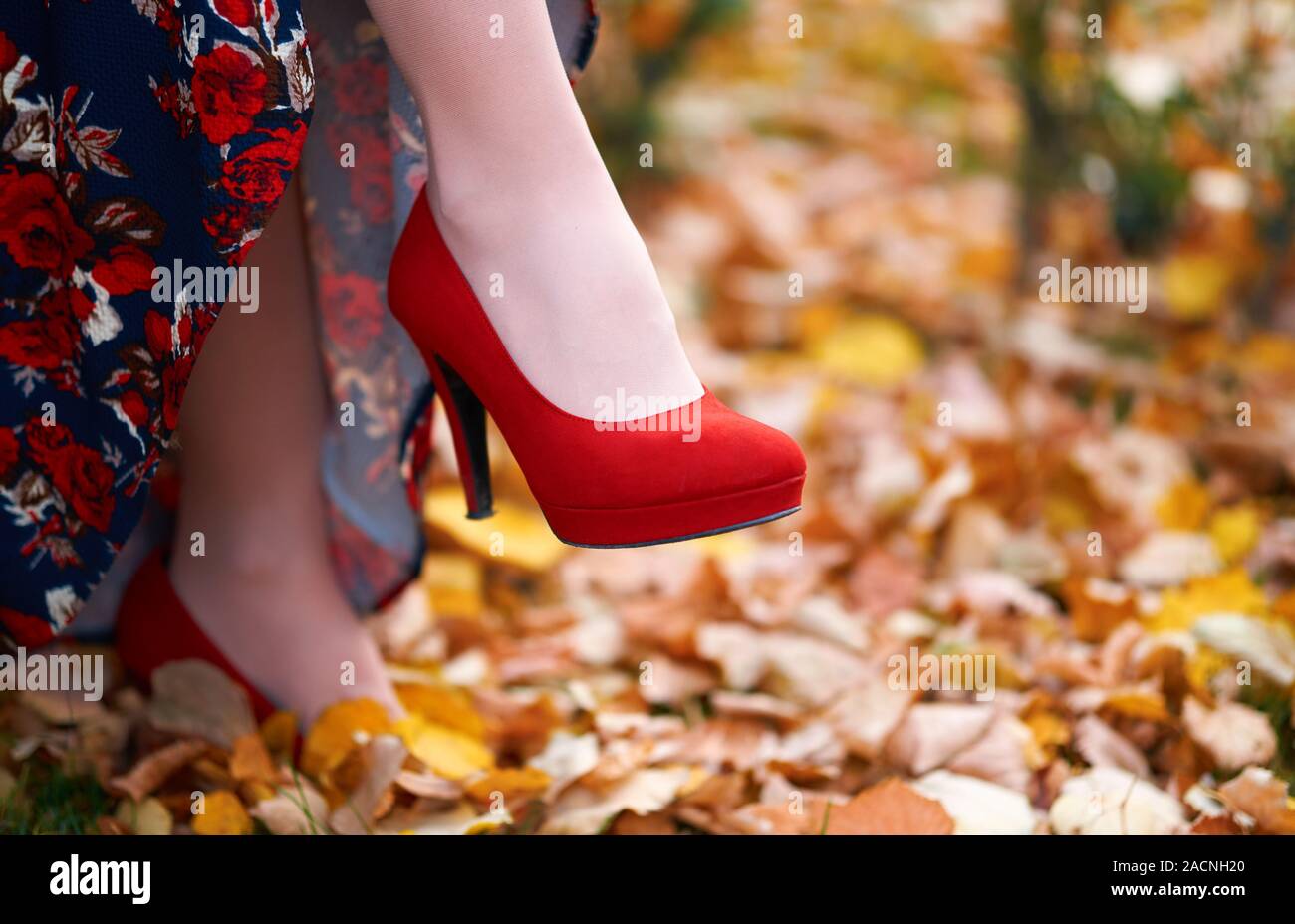 close up of women's feet shod in red high heels shoes, autumn season ...