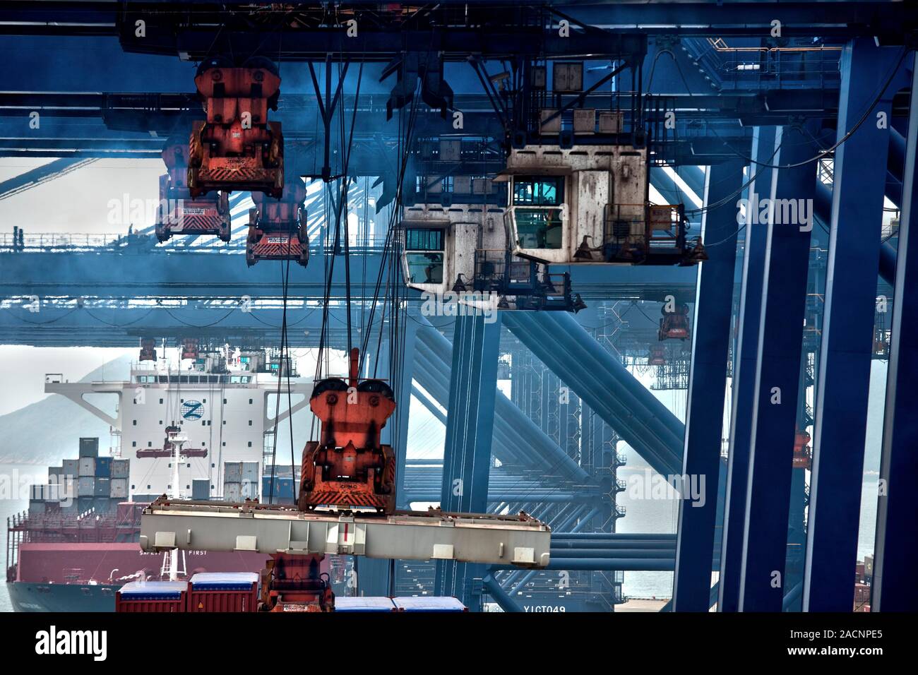 Yangshan Port. Workers operating the huge container handling cranes at ...
