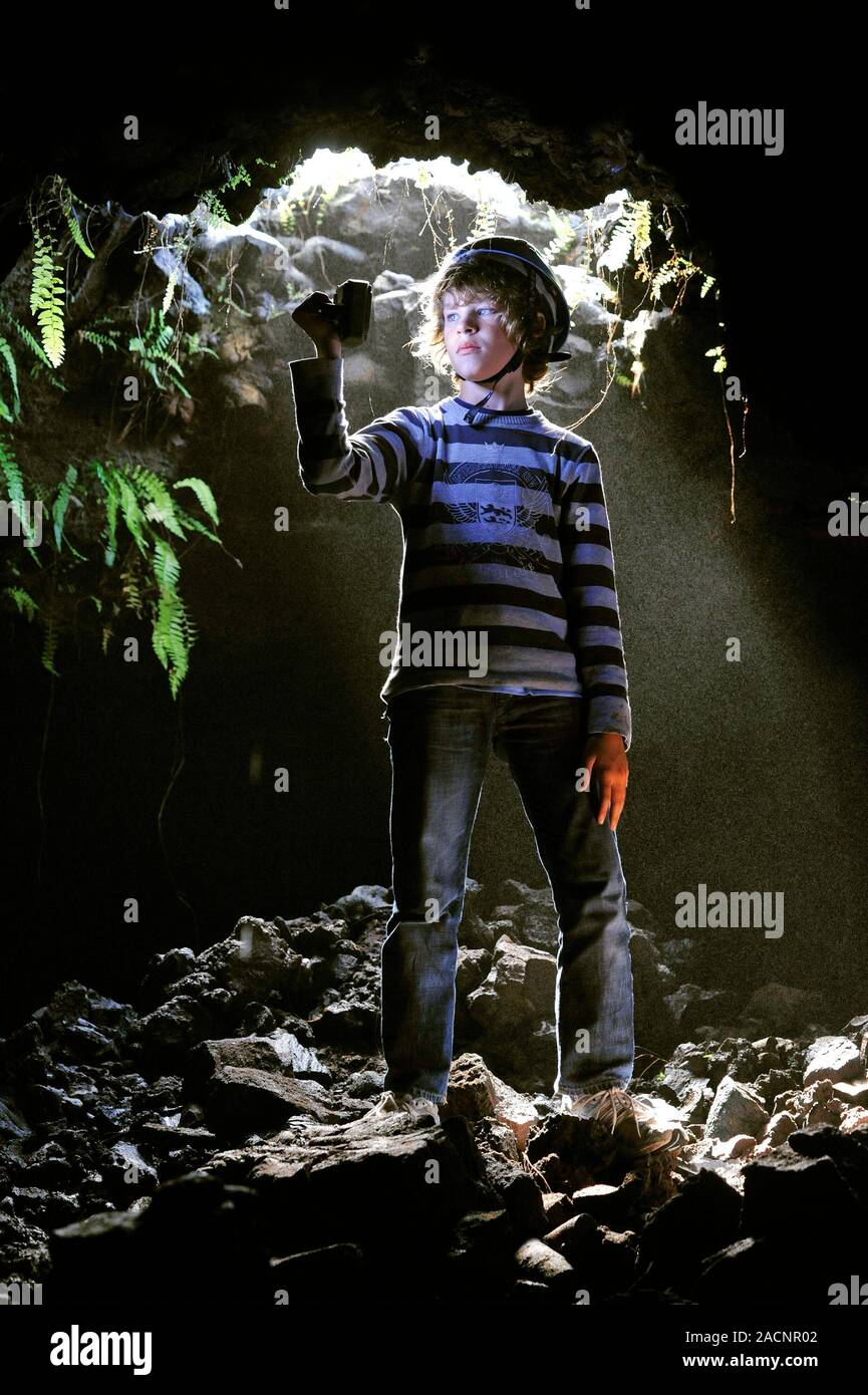 Lava cave exploration. Tourist at the entrance to a cave formed out of ...