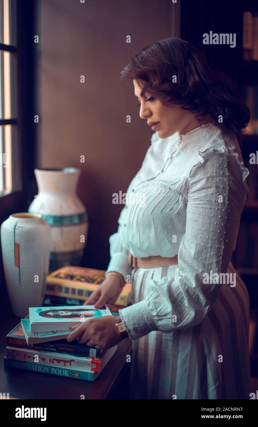 A Women Standing in Window Reading Book Stock Photo - Alamy