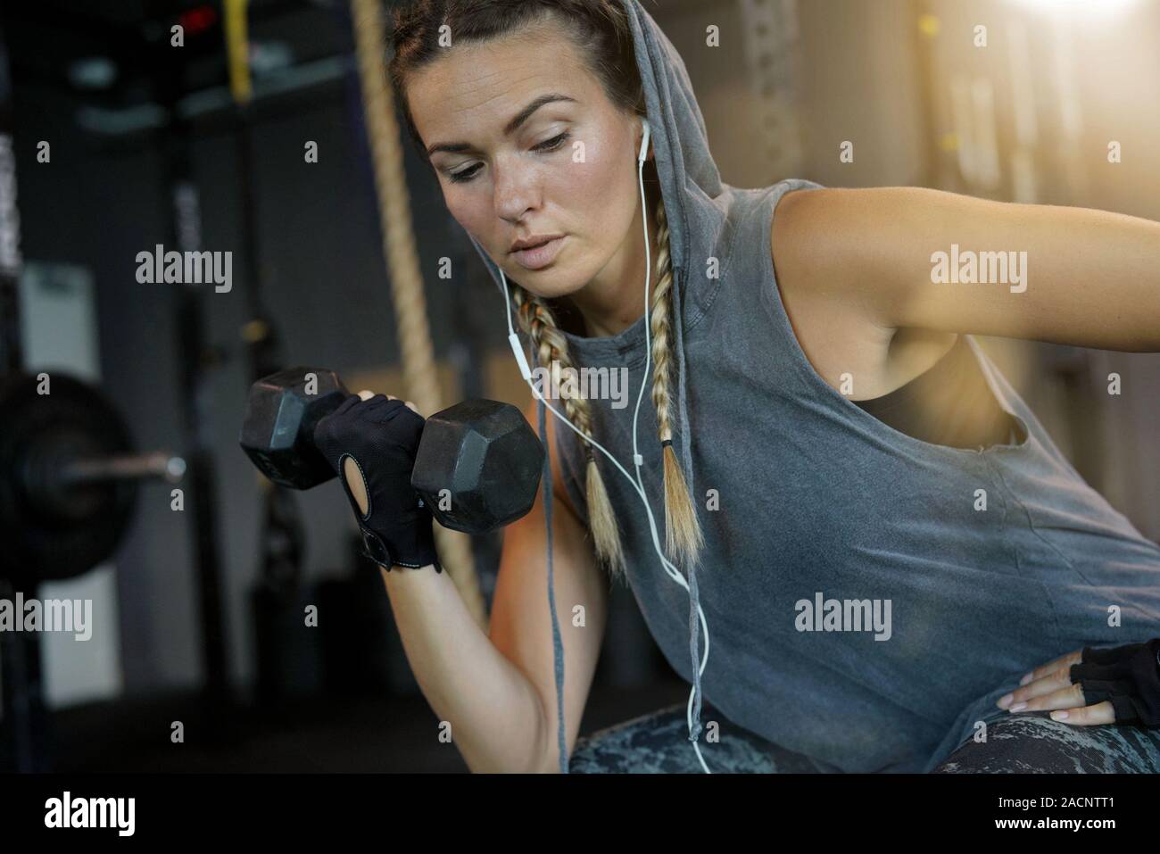 Woman in a gym working out, lifting weights and listening to music ...