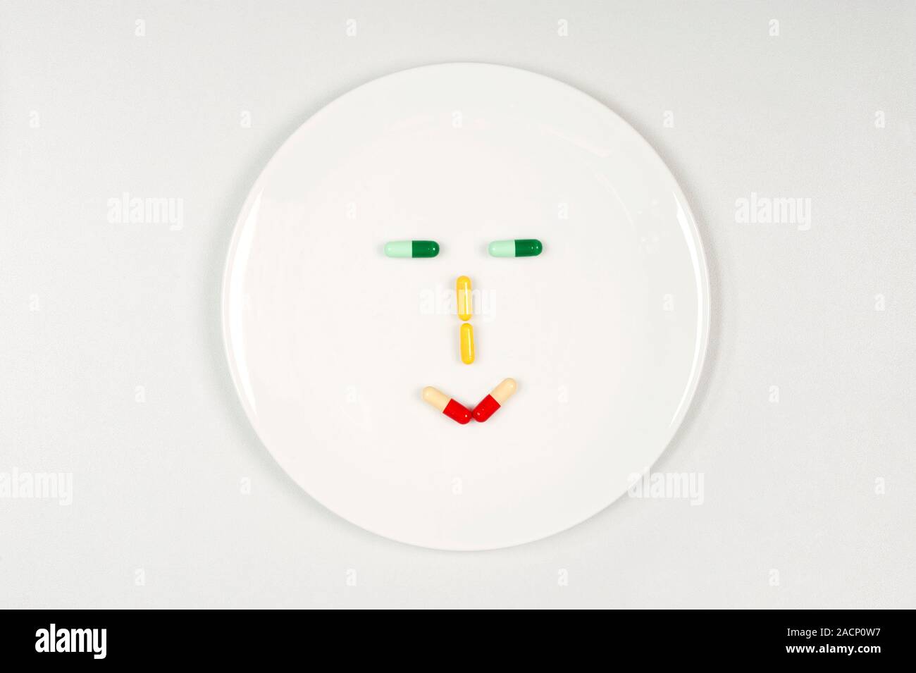 Happy pill face. Drug capsules arranged on a plate to represent a happy ...