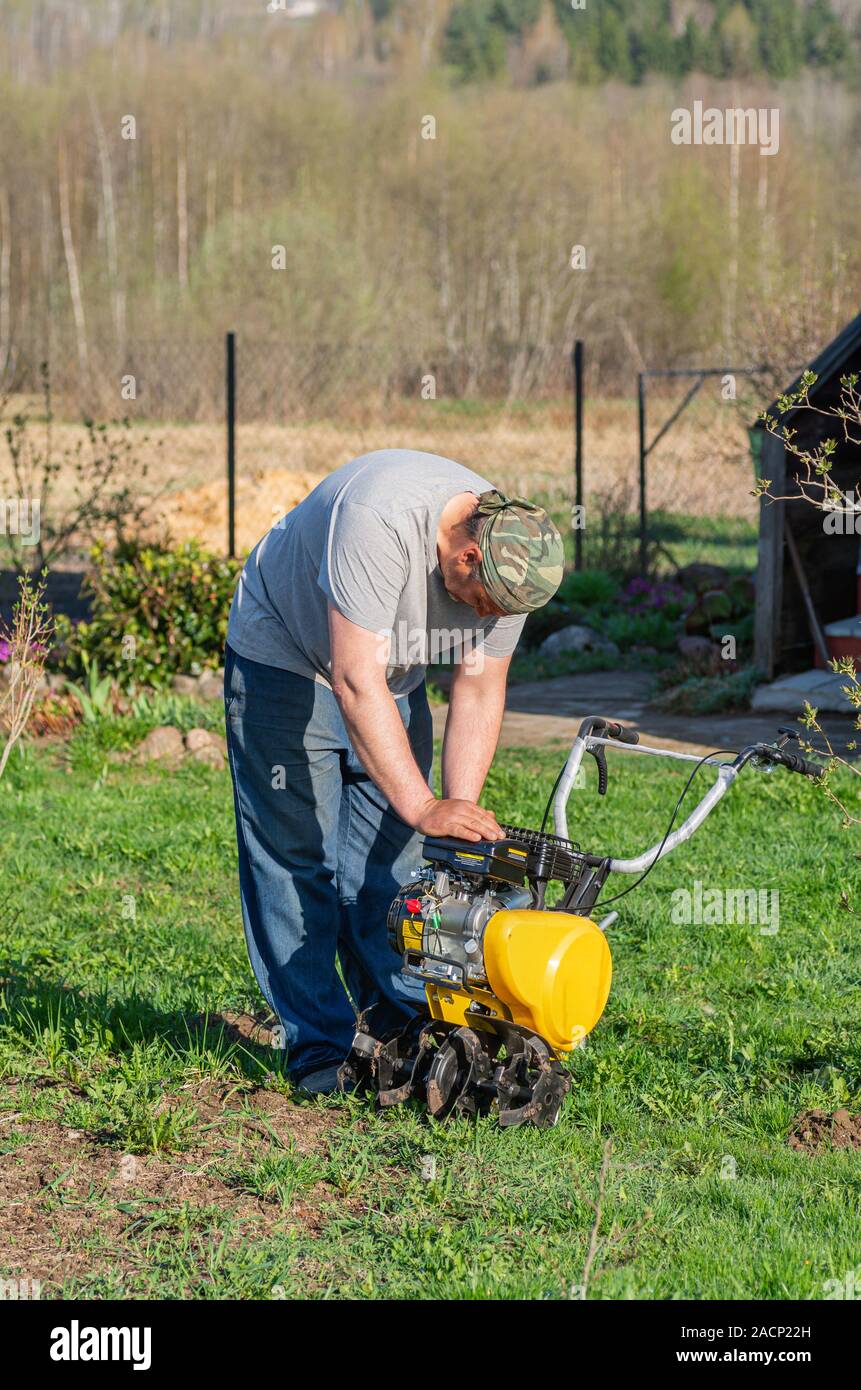A male farmer prepares a cultivator for work. Agricultural machinery ...