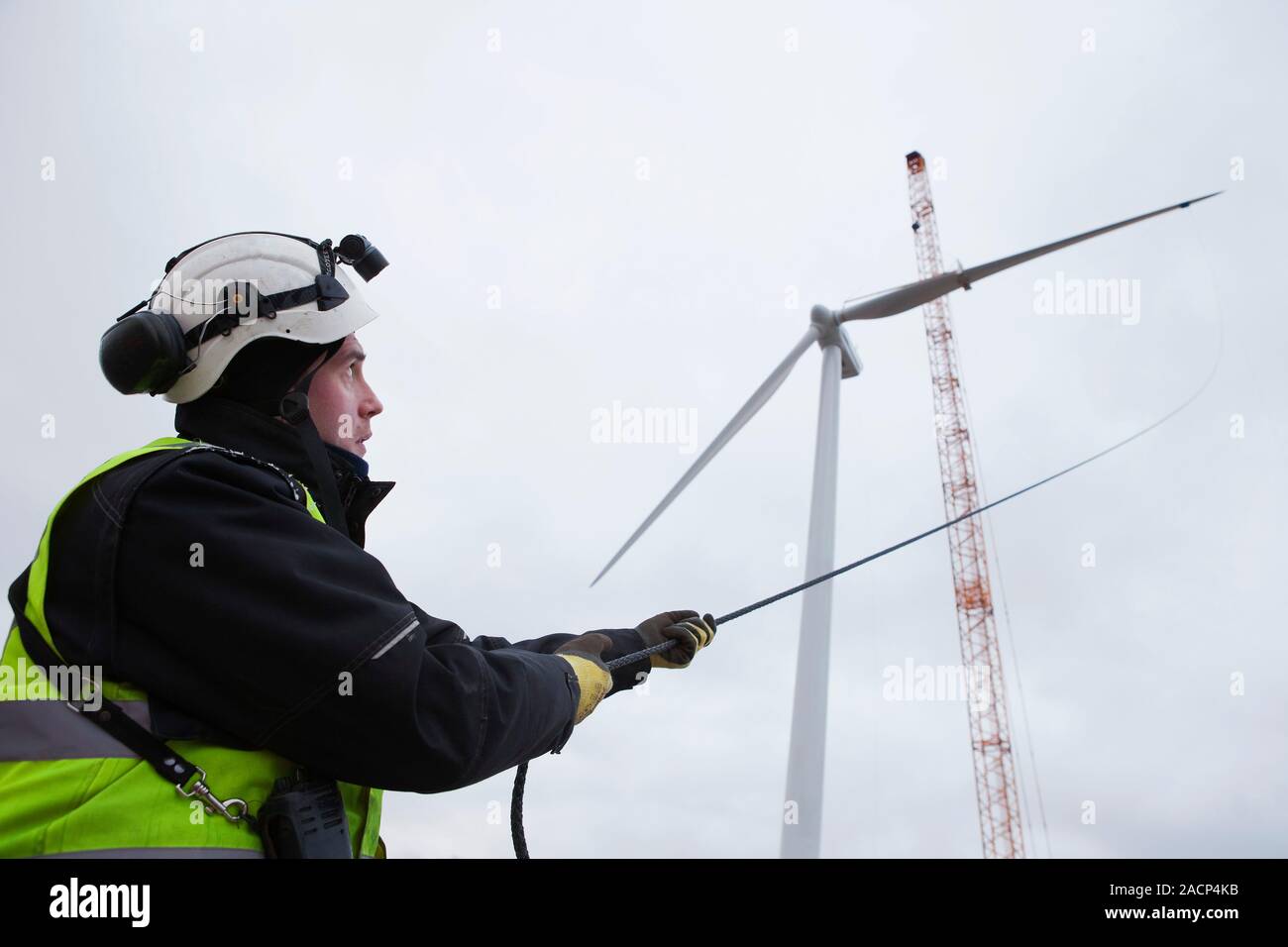 Wind turbine assembly. Industrial workers using a crane and tethers to ...