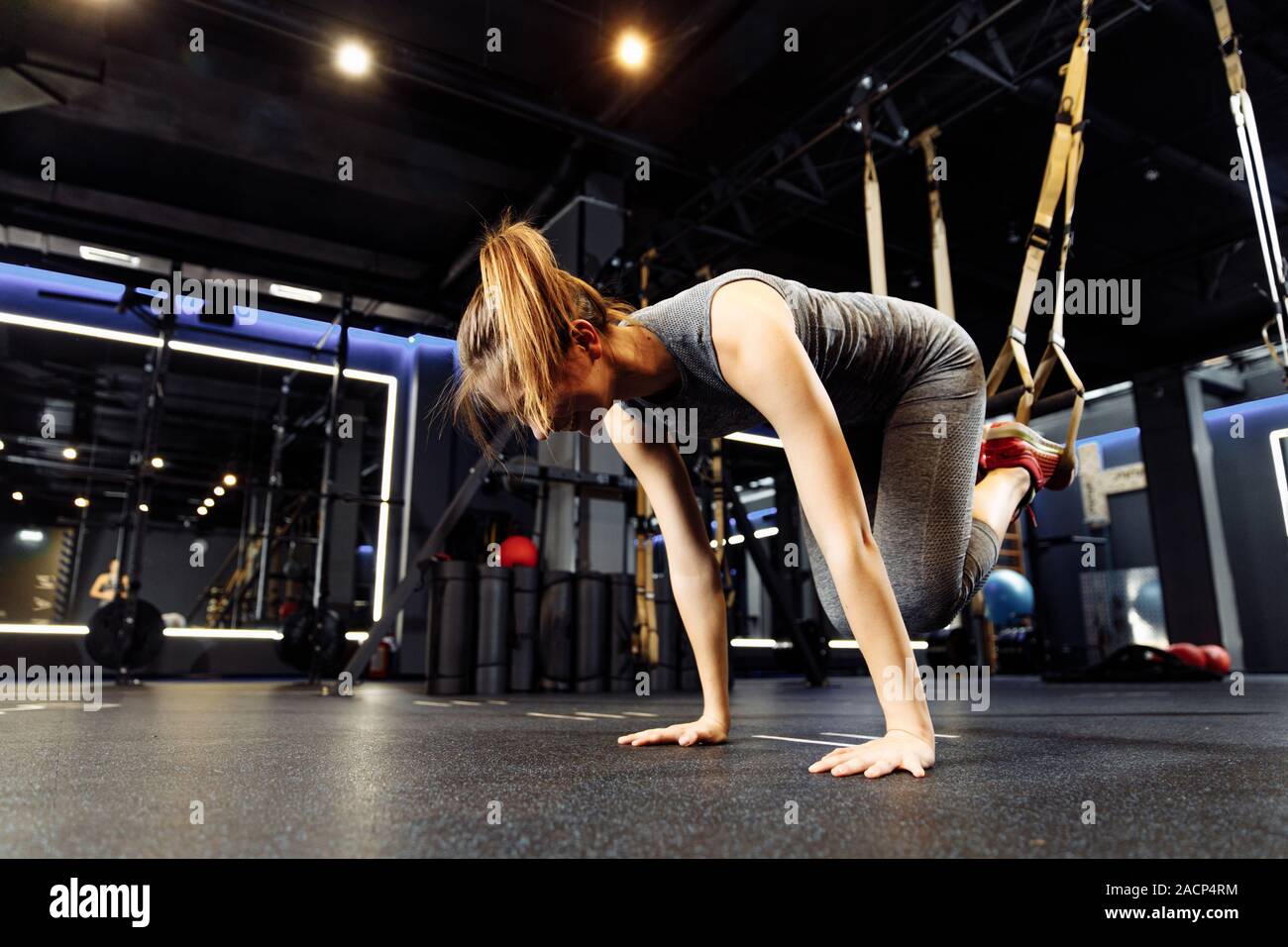 Athletic girl stretching with elastic bands in gym on dark background ...