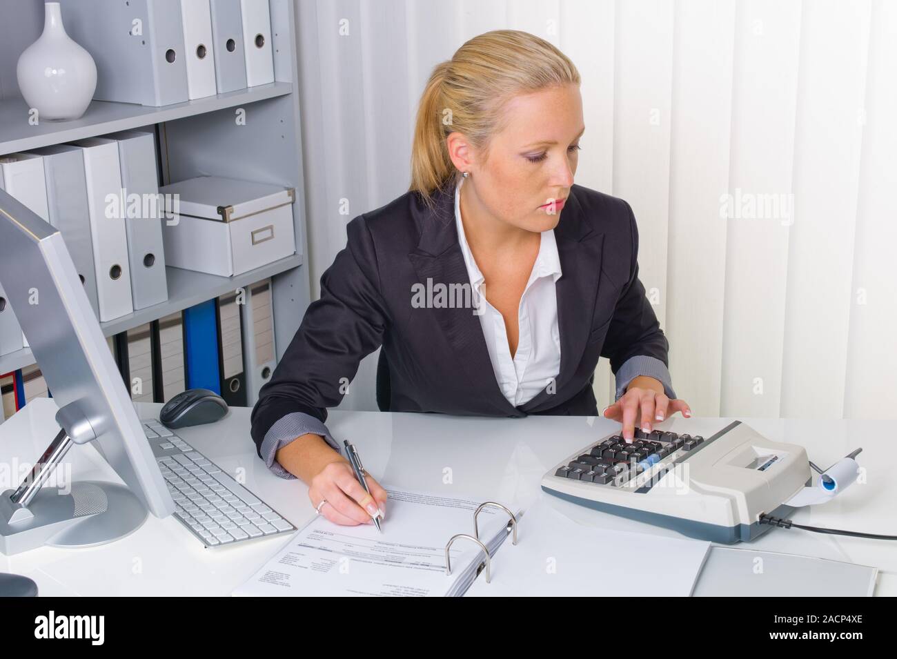 Woman in office with calculating machine Stock Photo - Alamy