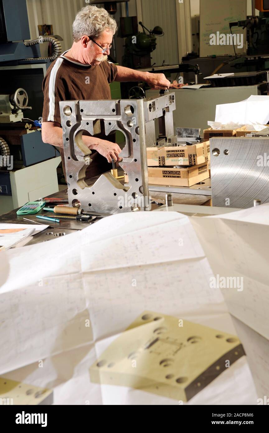 Injection moulding. Worker assembling an injection mould used to shape ...
