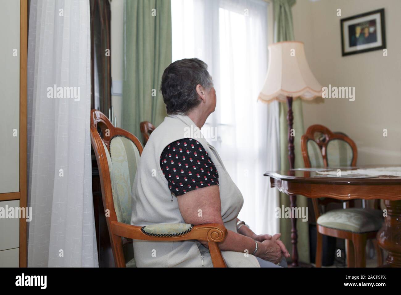 Grieving woman, looking at a framed, wall-mounted photograph of her and ...