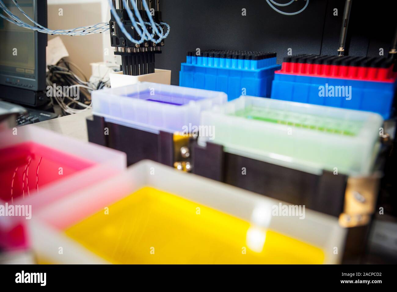 Pipetting robot in a lab. Close-up of vats of coloured liquids in a robotic pipetting machine in ...