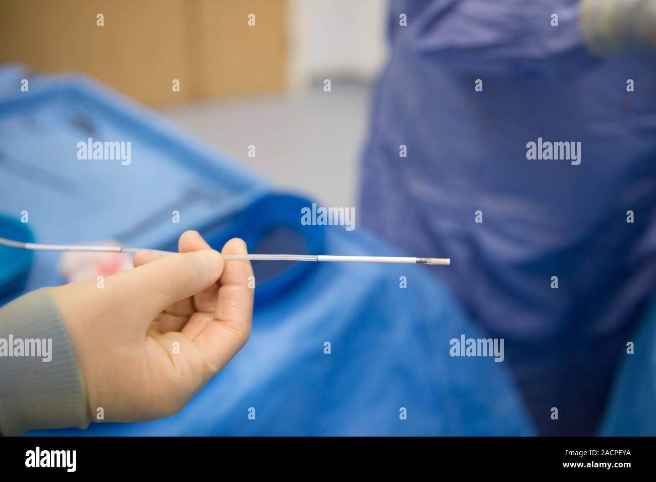 Implantable defibrillator surgery. Surgeon holding a wire for insertion ...