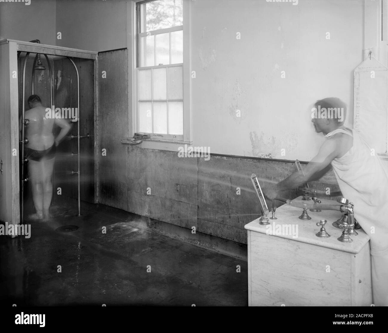 Hospital hydrotherapy. Physiotherapy worker (right) applying jets of ...