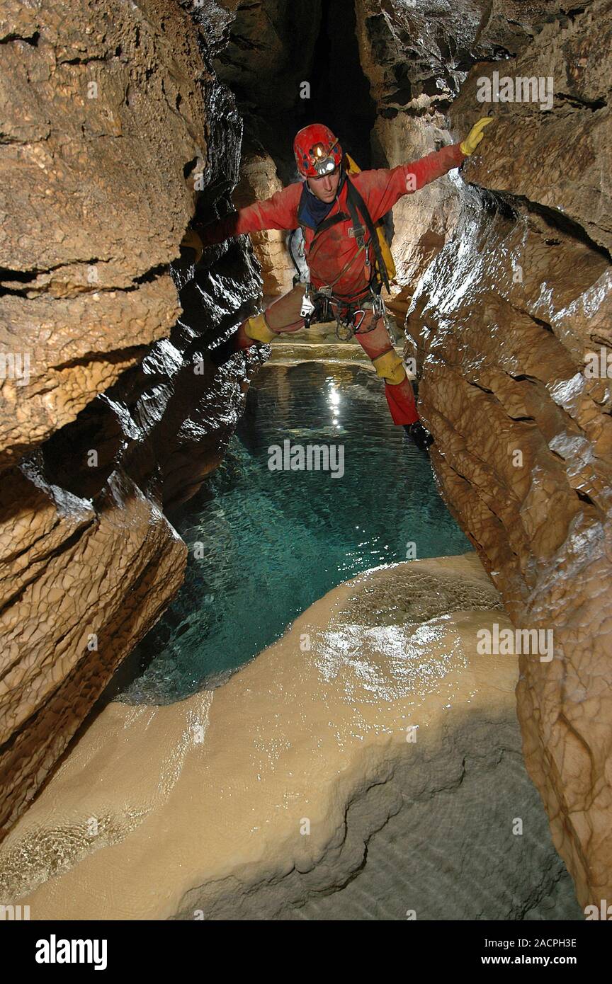 Cave exploration. Caver exploring a waterway in the Choranche cave ...
