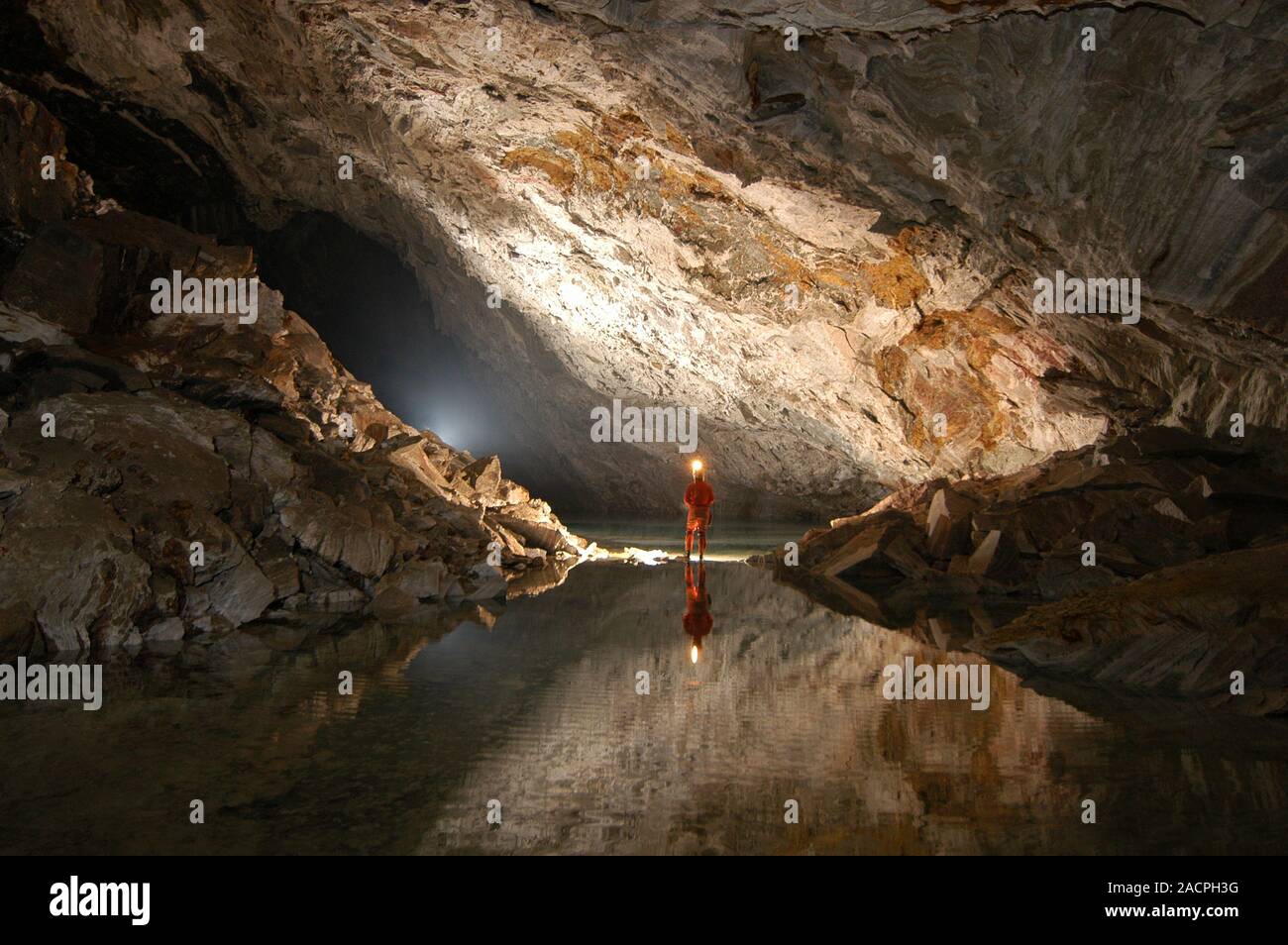 Cave exploration. Caver exploring a waterway in the Choranche cave ...