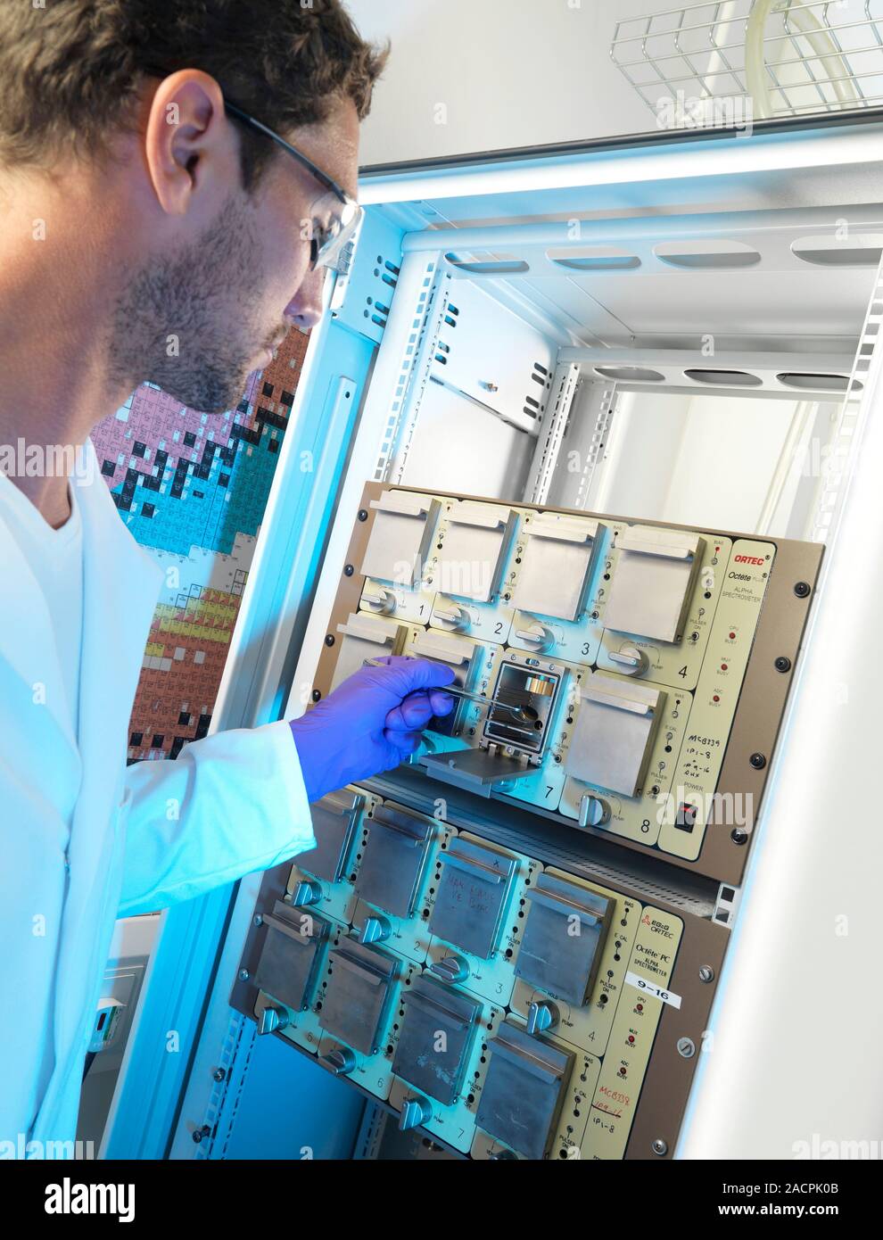 Alpha spectroscopy. Scientist loading a sample that has been dried onto ...
